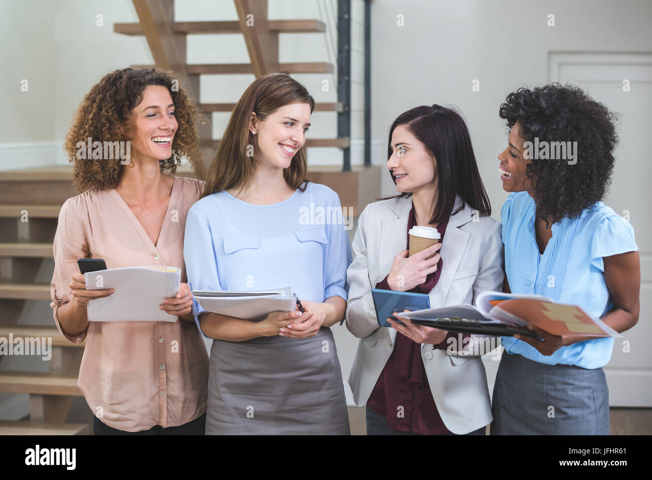 Female business colleagues standing together with file and digital ...
