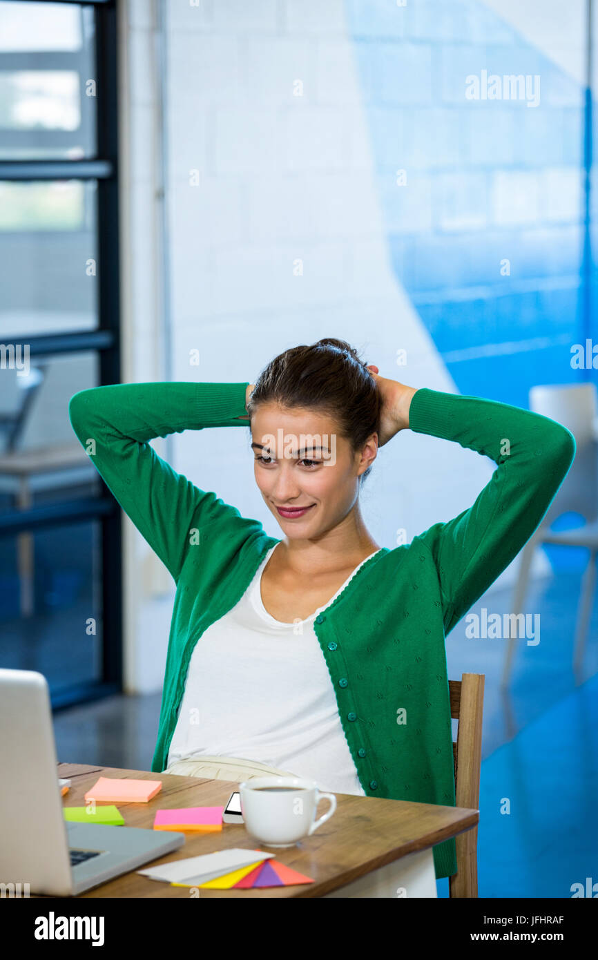 Woman relaxing on chair with hands behind head Stock Photo - Alamy