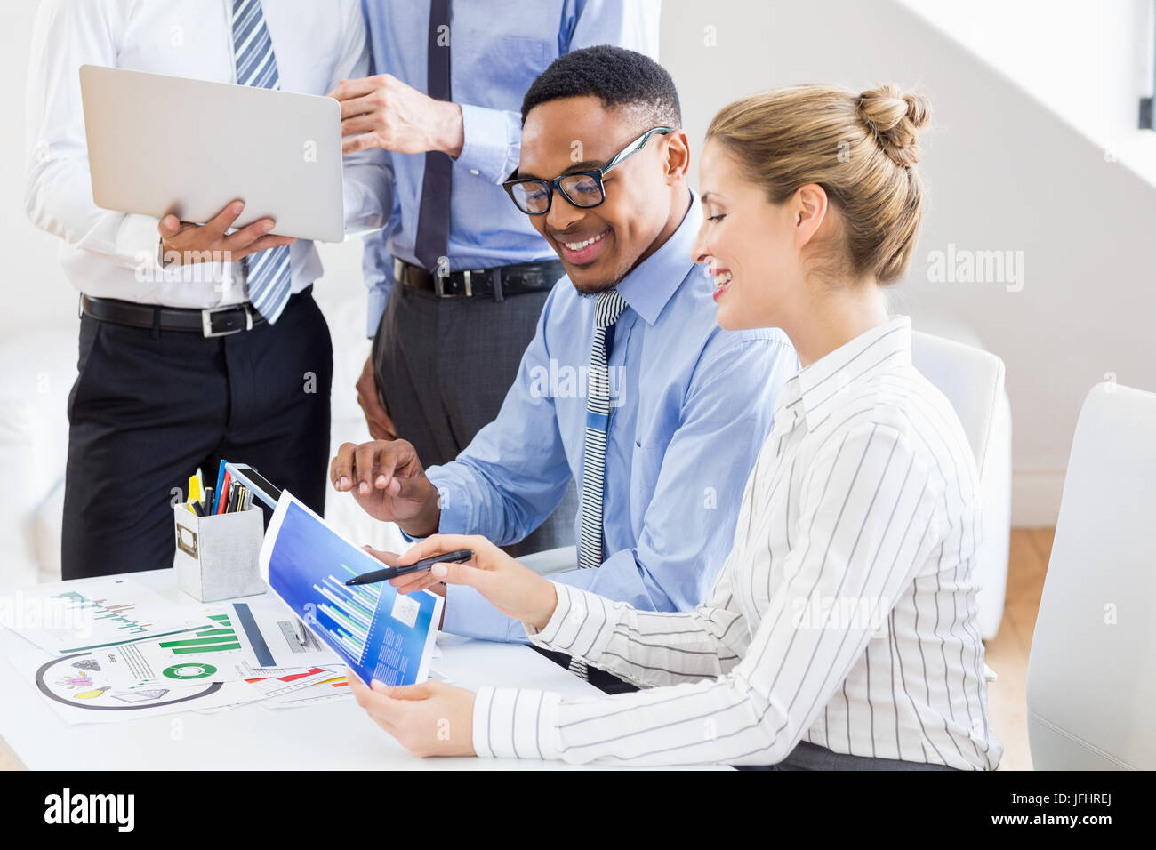 Happy business colleagues reviewing a report at desk Stock Photo - Alamy