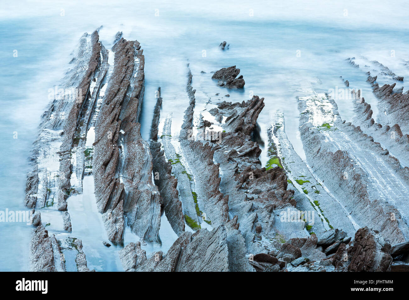 Twilight ocean coast with ribbed stratiform rock Stock Photo - Alamy