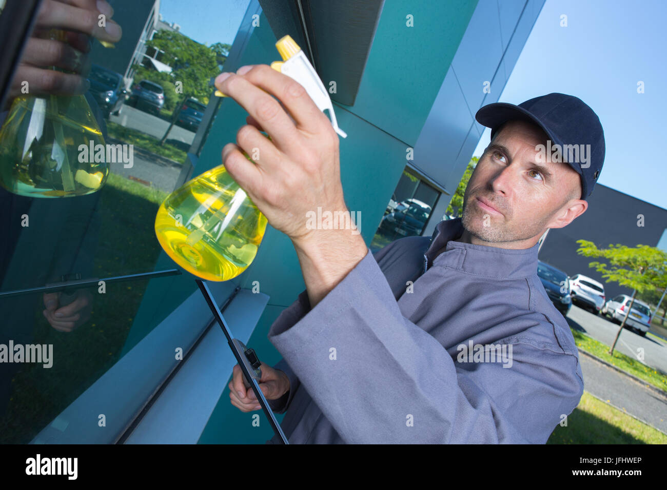 Male window cleaner spraying product Stock Photo - Alamy