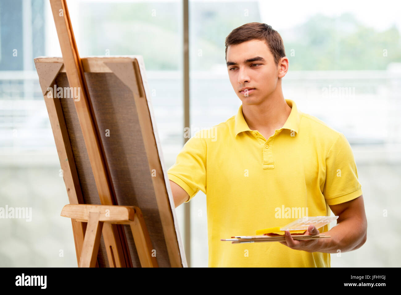 Young male artist drawing pictures in bright studio Stock Photo - Alamy