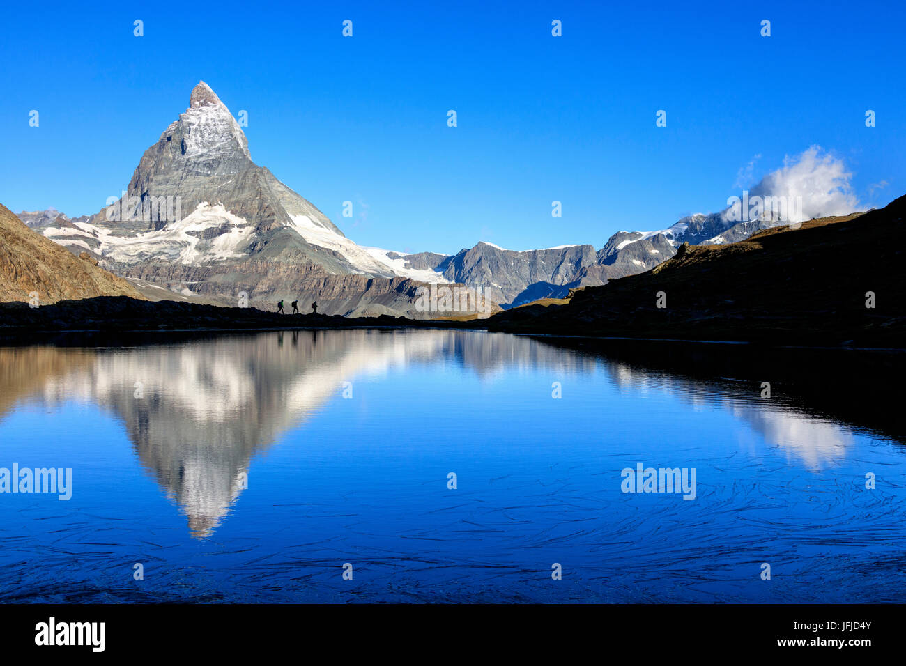 Hikers admire the Matterhorn reflected in Lake Stellisee Zermatt Canton ...