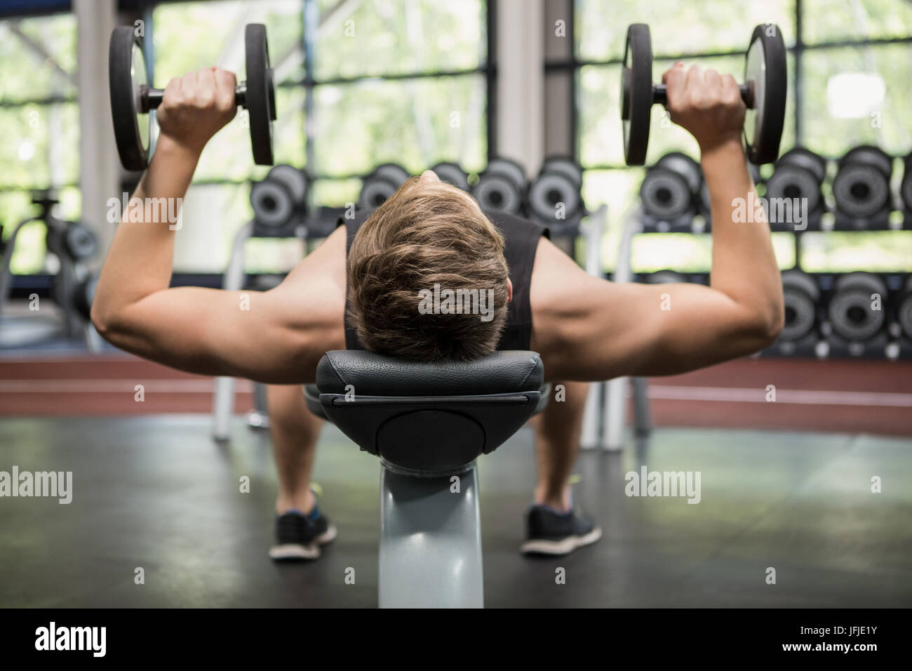 Man lifting dumbbell weights while lying down Stock Photo - Alamy