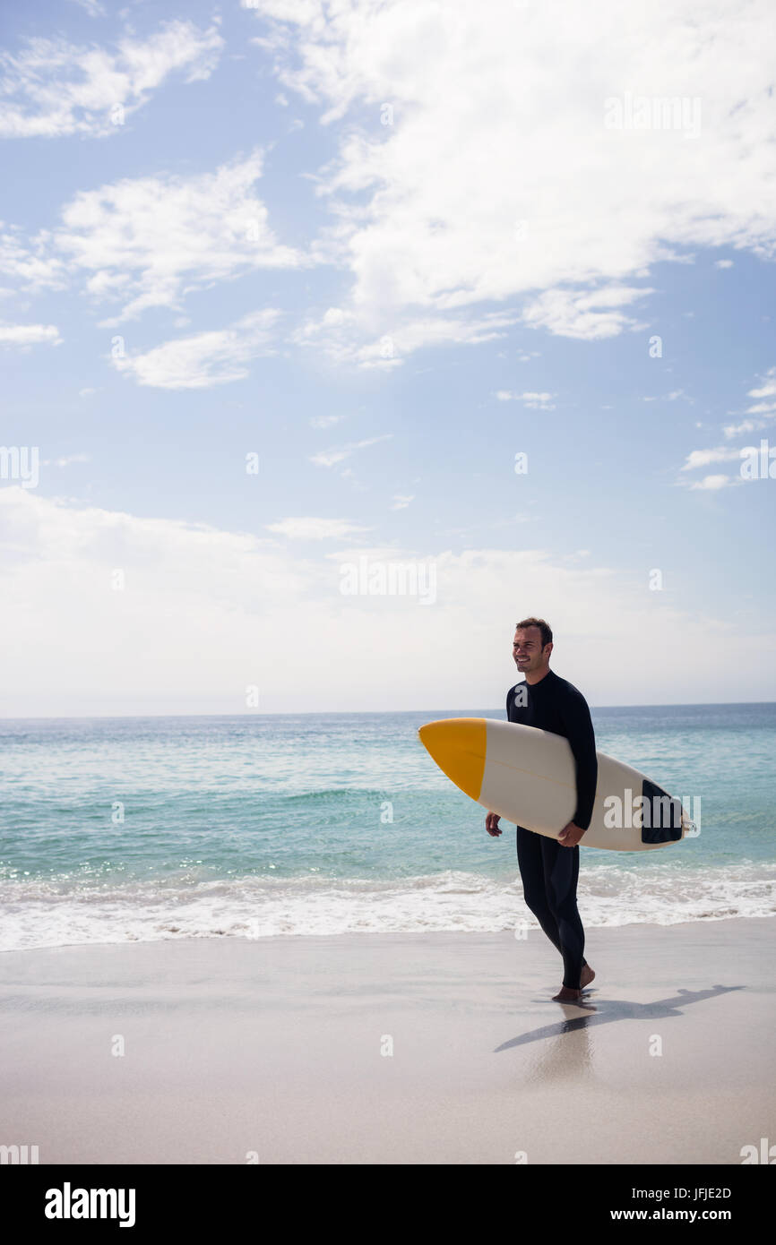 Happy surfer holding a surfboard on the beach Stock Photo - Alamy