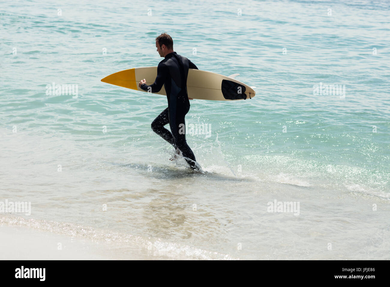 Surfer running on the beach with a surfboard Stock Photo - Alamy