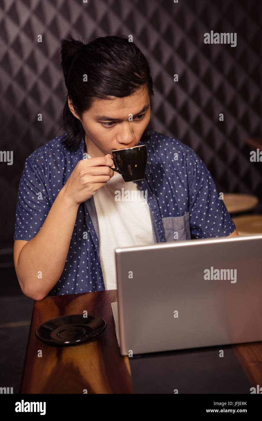 Man using a laptop and drinking coffee Stock Photo - Alamy