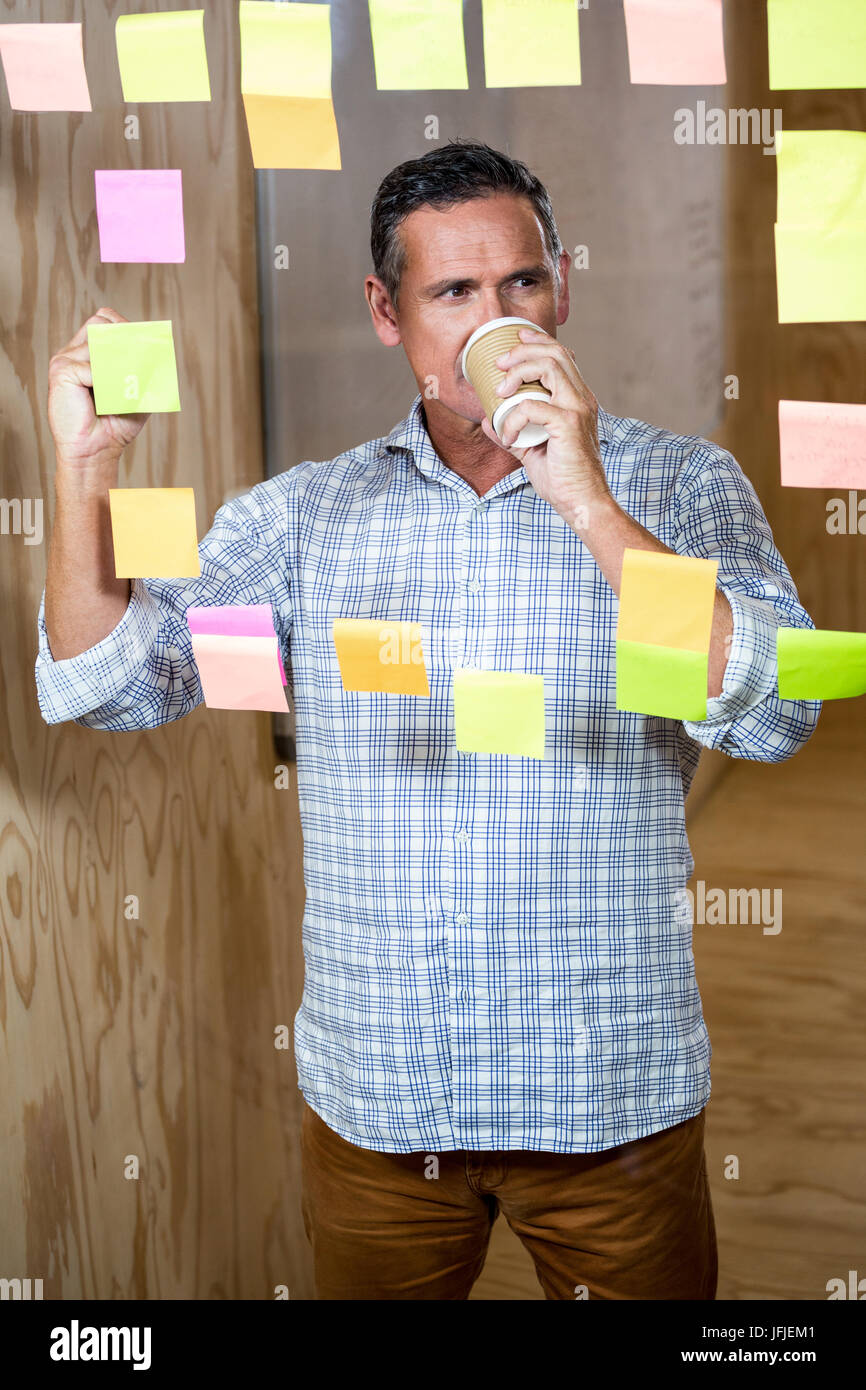 Man writing on sticky notes while having coffee Stock Photo - Alamy