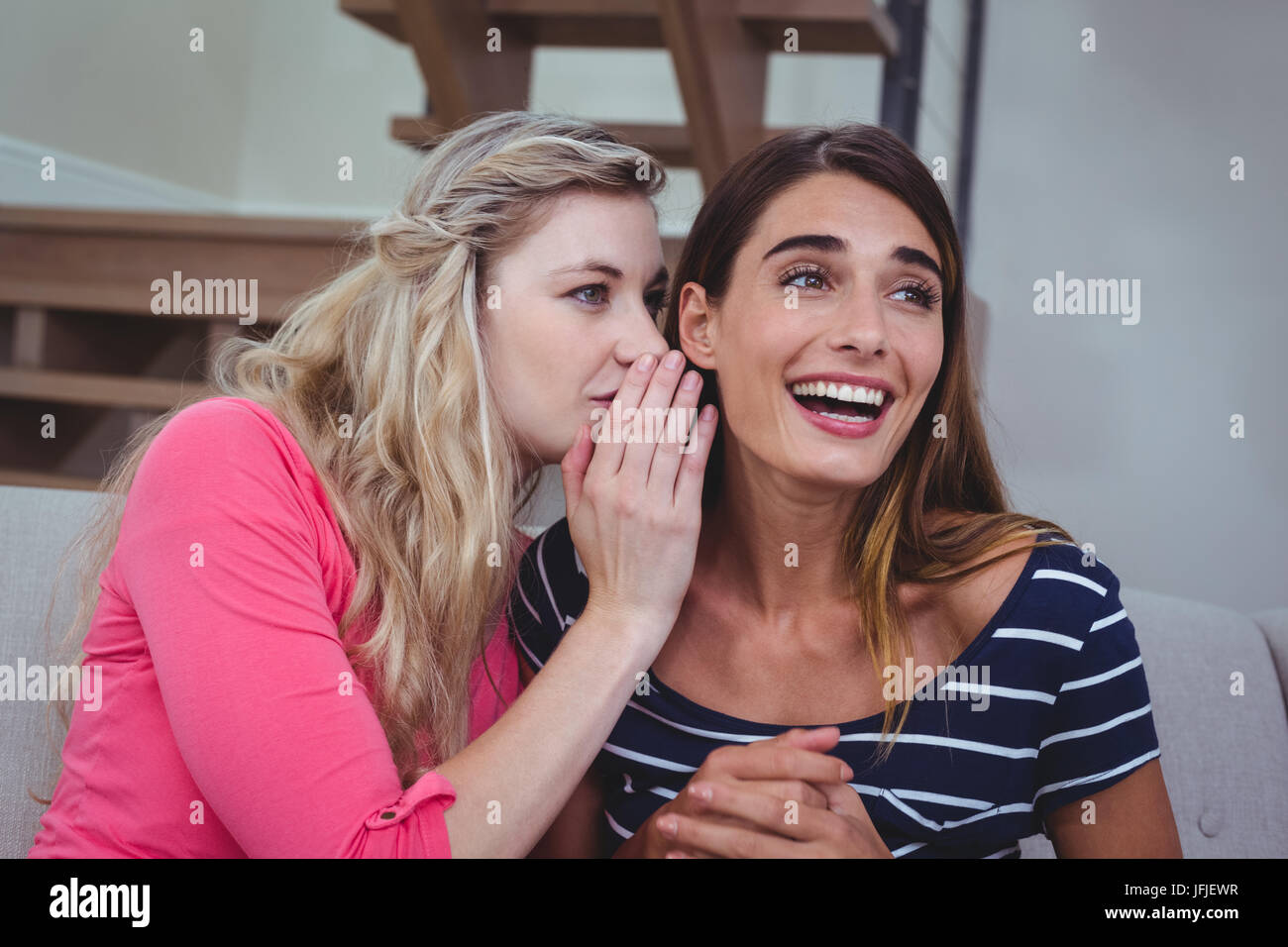 Young woman whispering a secret to her friend Stock Photo - Alamy