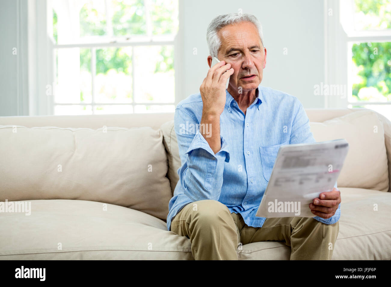 Old man talking on phone in living room at home Stock Photo - Alamy