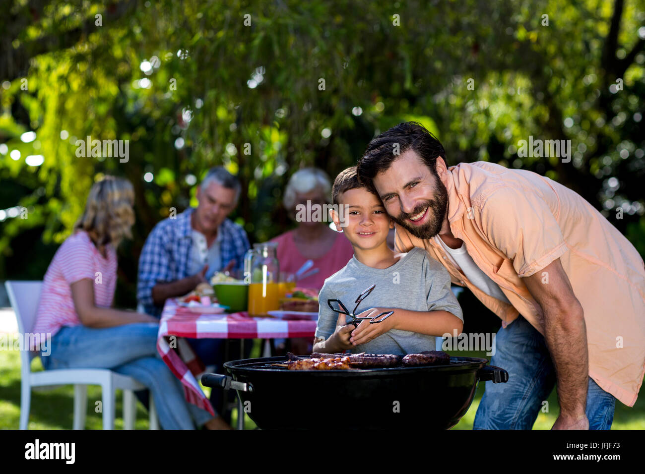Smiling father with son by barbecue grill in yard Stock Photo - Alamy