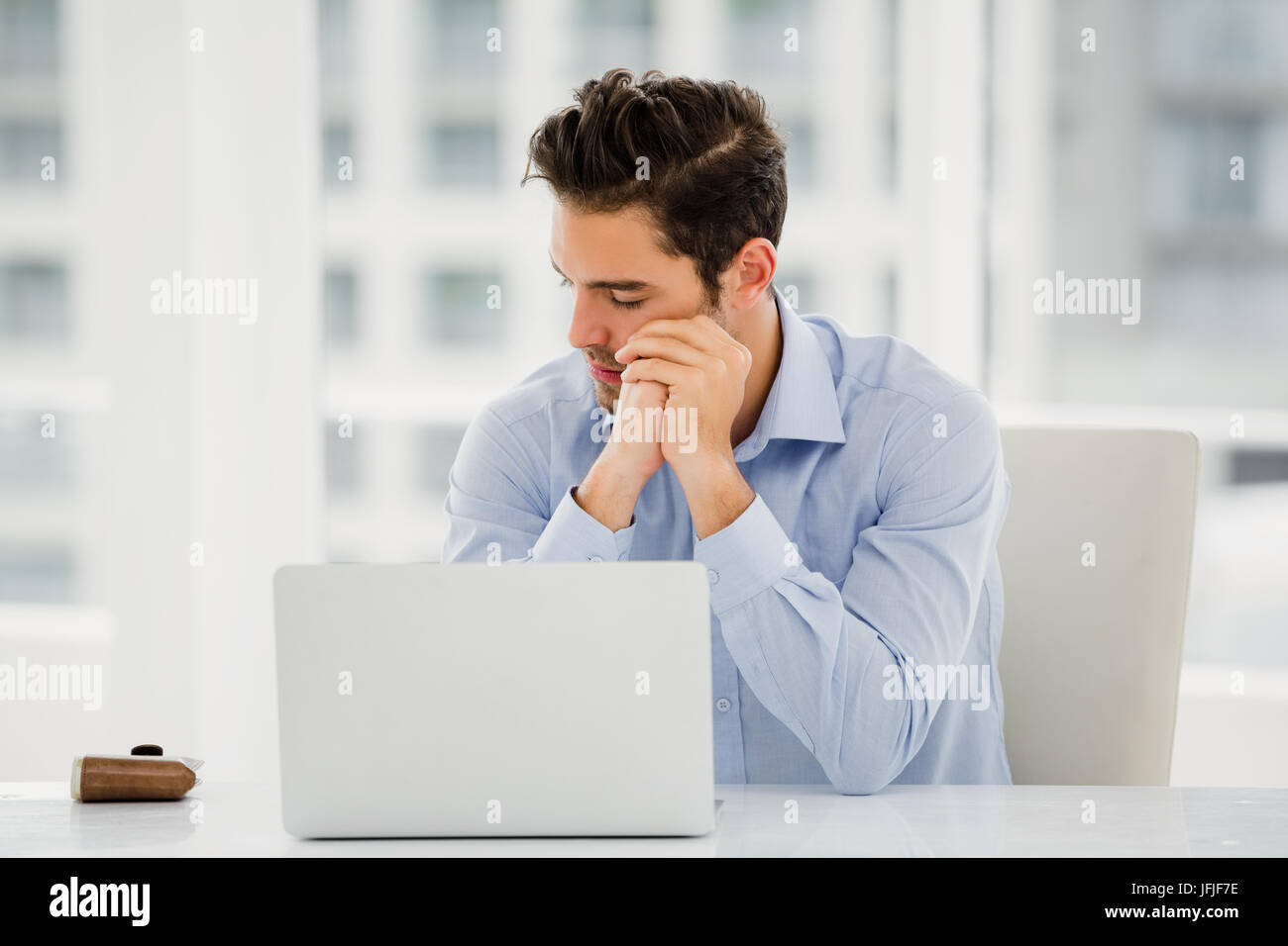 Tensed businessman sitting at table with laptop Stock Photo - Alamy