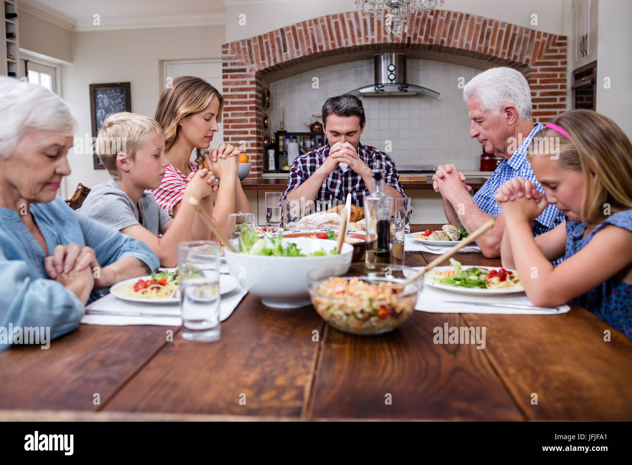 Multi-generation family praying before having meal Stock Photo - Alamy
