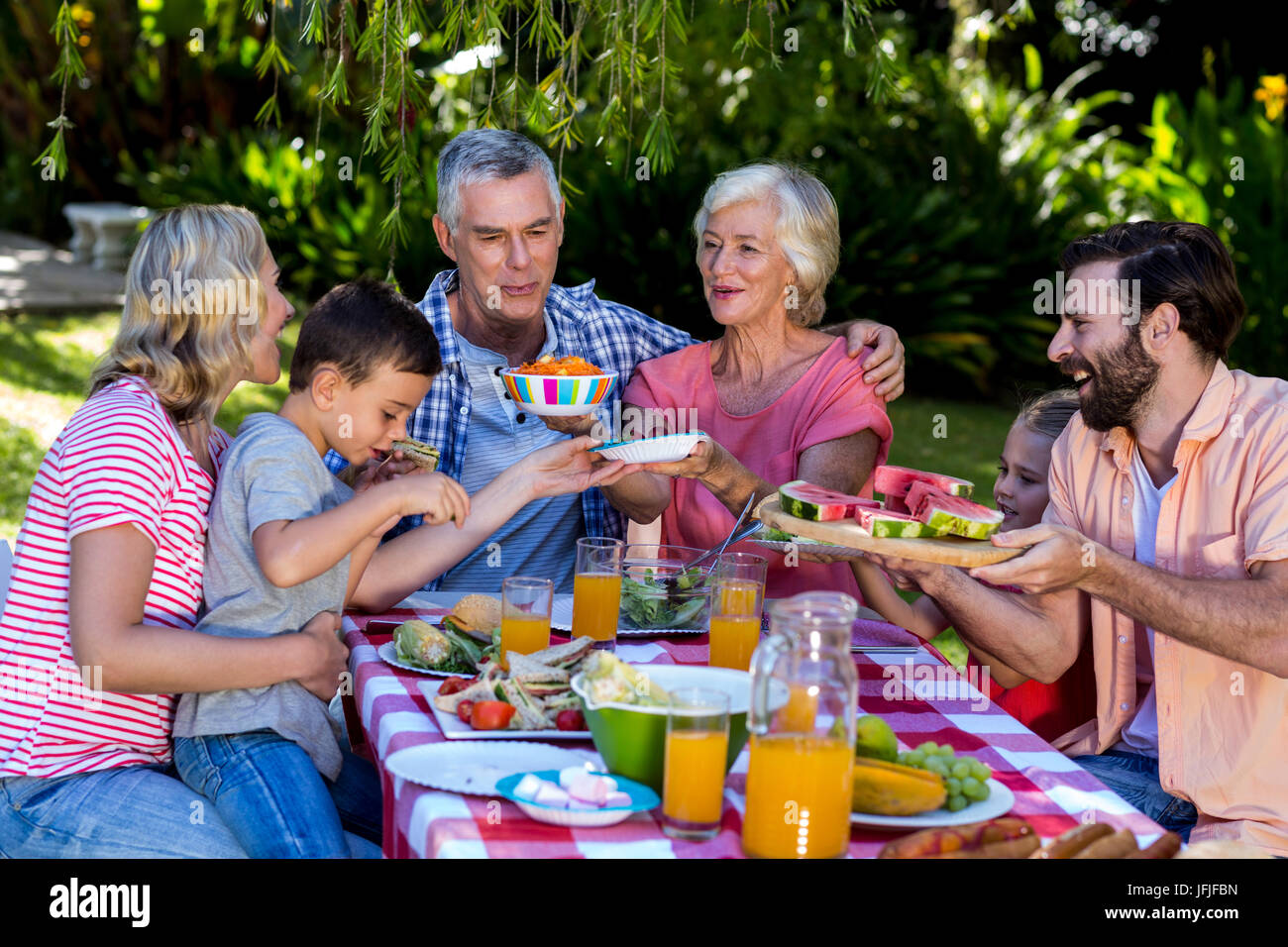 Multi- generation family offering food at breakfast Stock Photo - Alamy