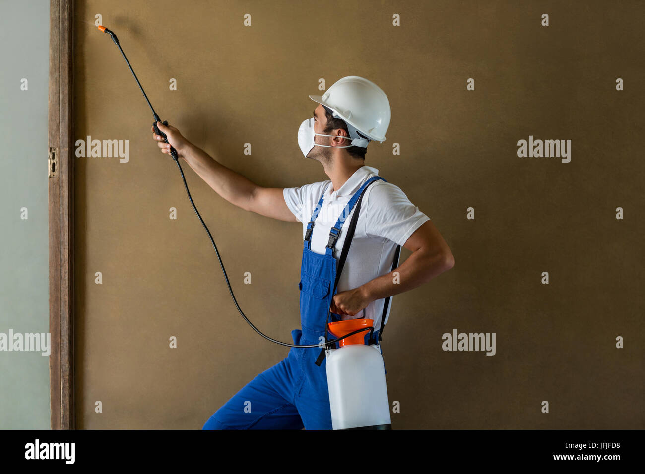 Side view of manual worker spraying chemical on wall Stock Photo - Alamy