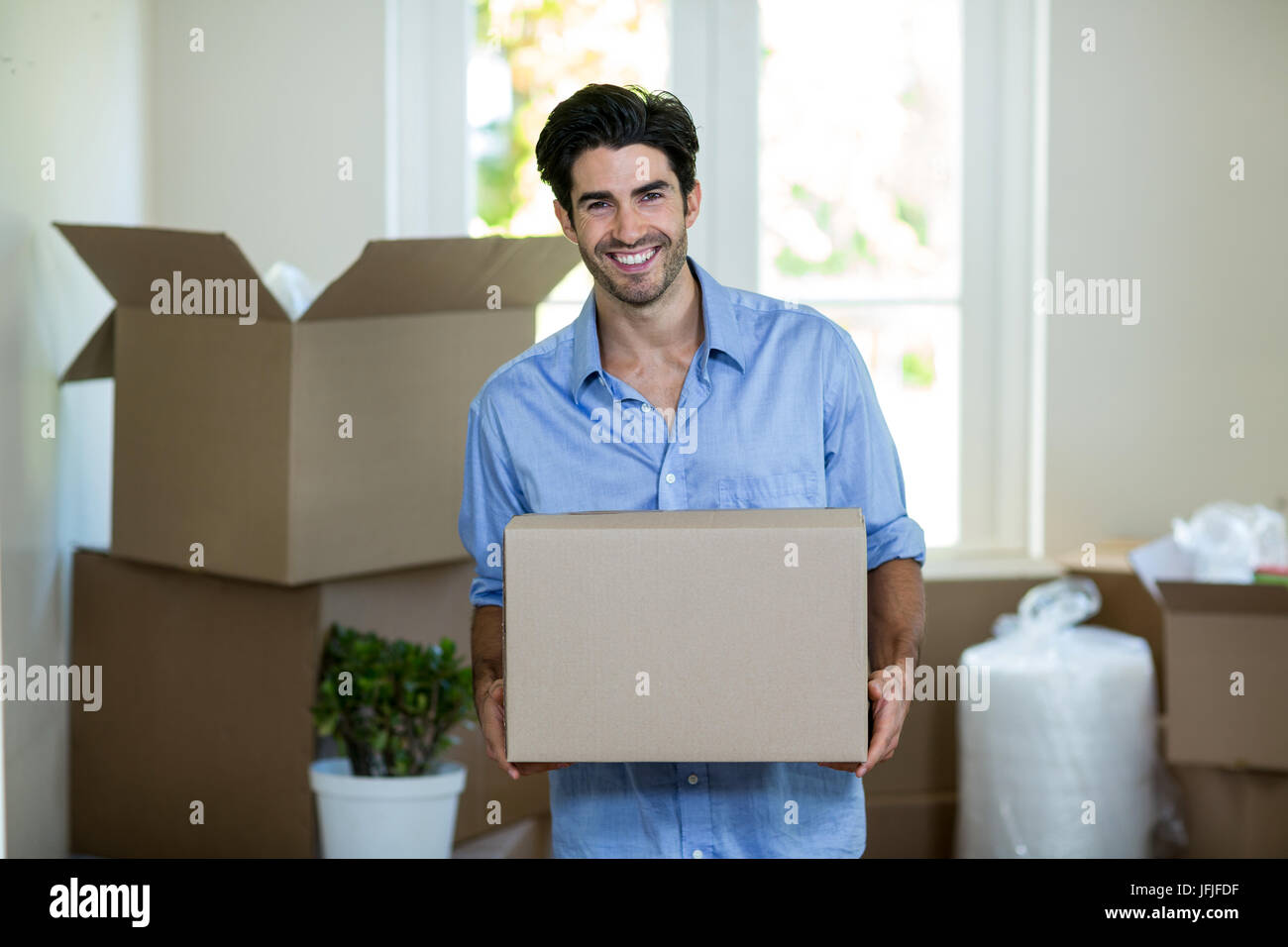 Young man standing with unpacking carton boxes in house Stock Photo - Alamy