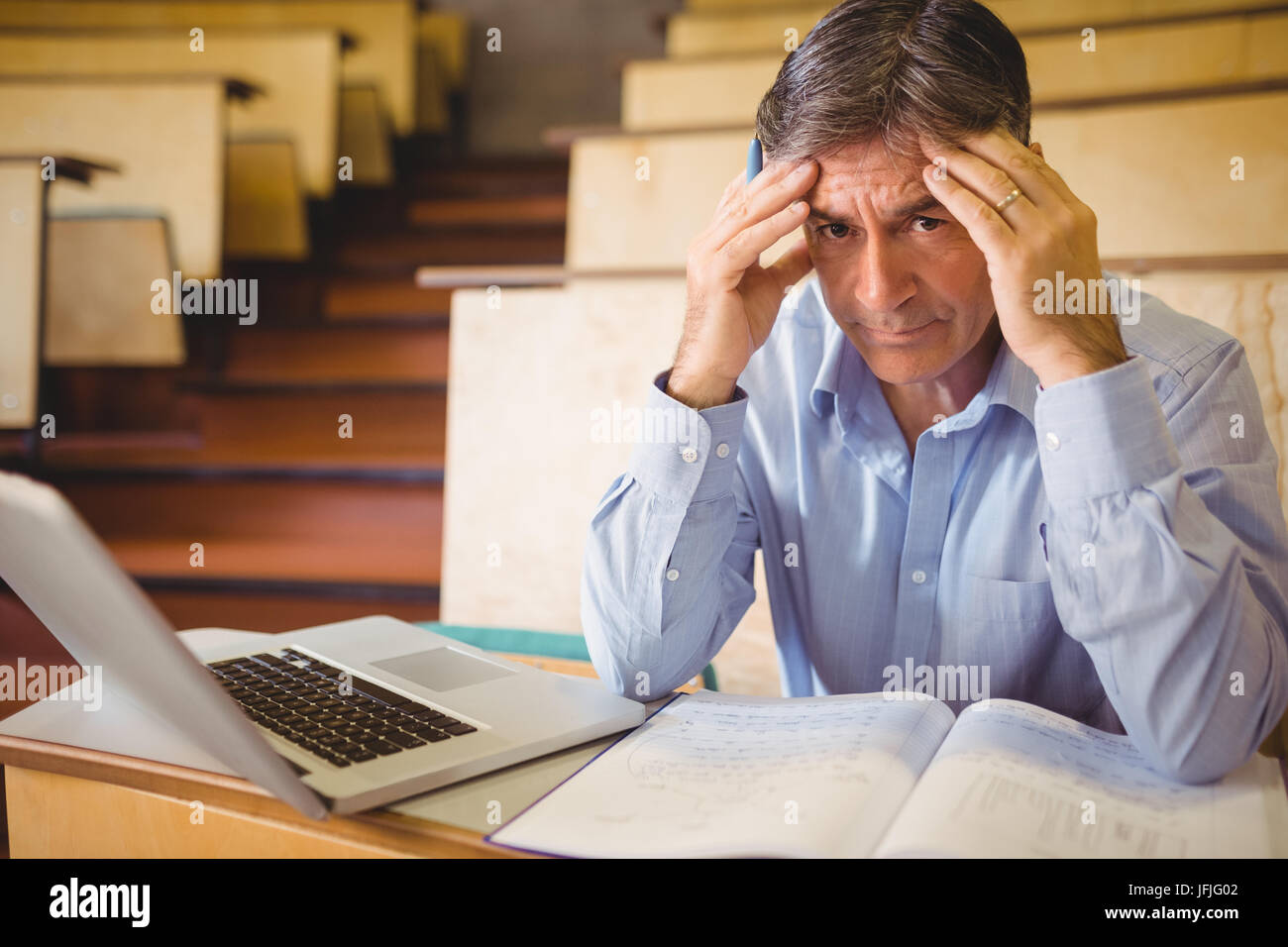 Depressed professor sitting with notes and laptop Stock Photo - Alamy