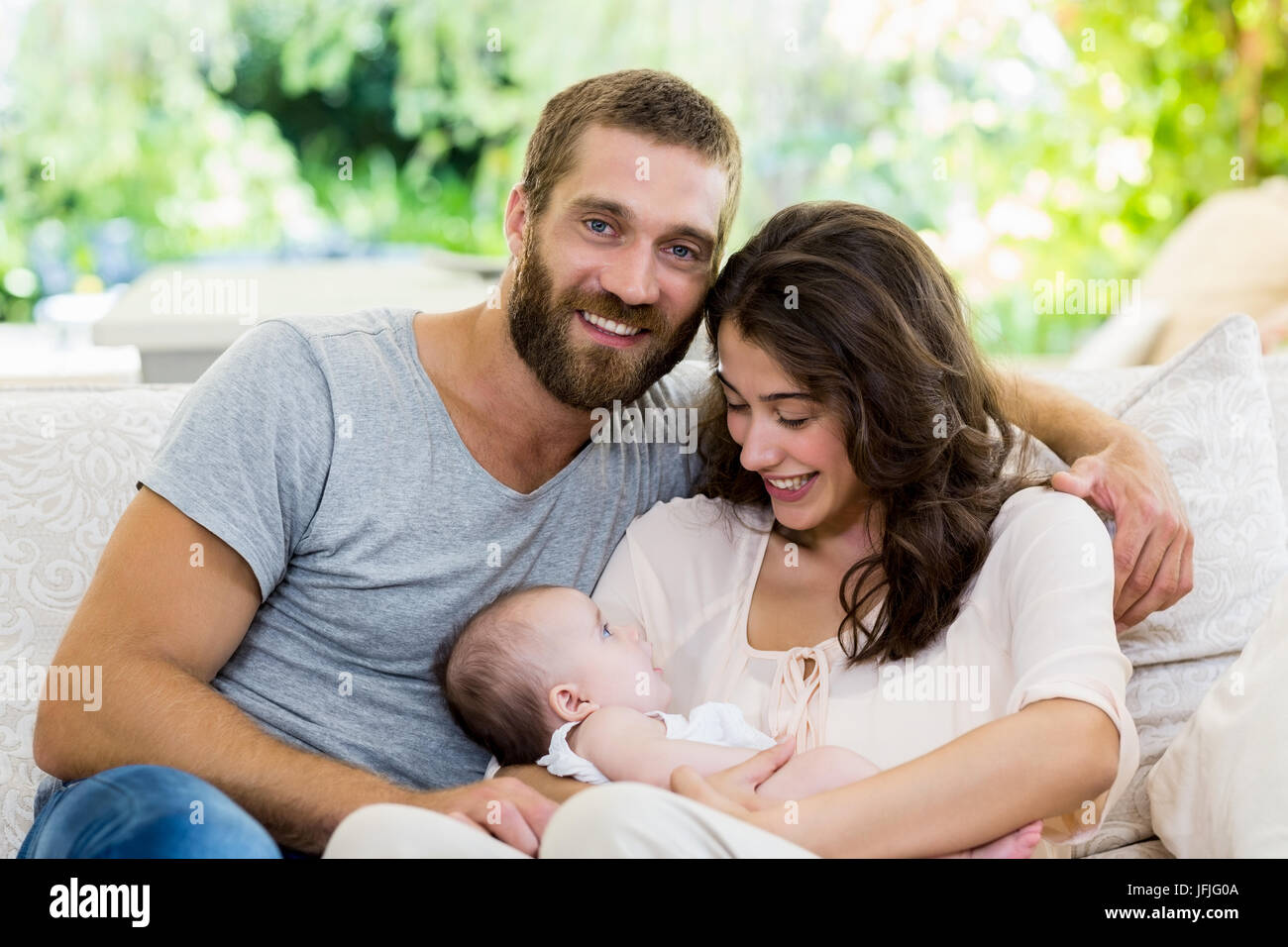 Happy parents with their baby in living room Stock Photo - Alamy