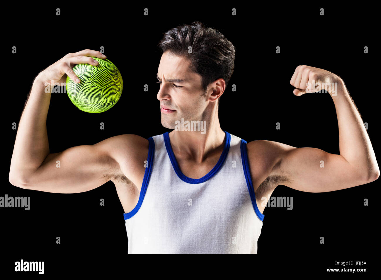 Confident athletic man holding ball and showing muscles Stock Photo - Alamy