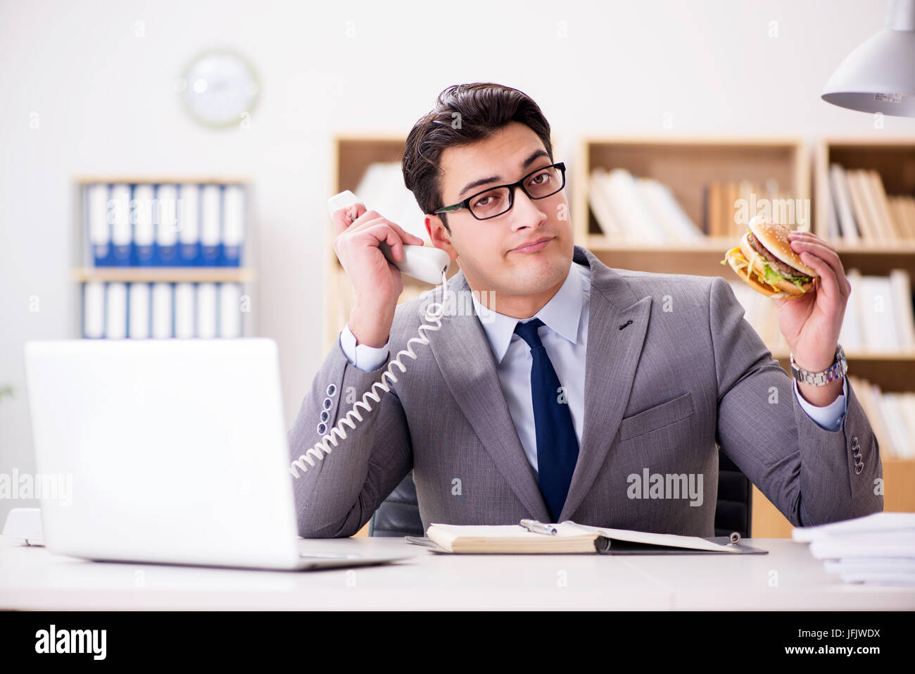 Hungry funny businessman eating junk food sandwich Stock Photo - Alamy