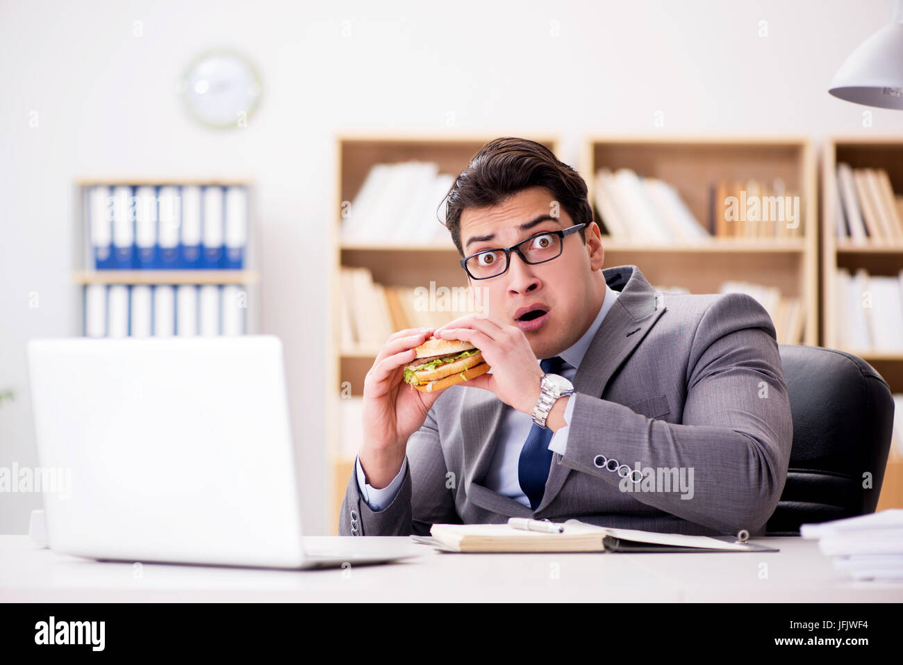 Hungry funny businessman eating junk food sandwich Stock Photo - Alamy