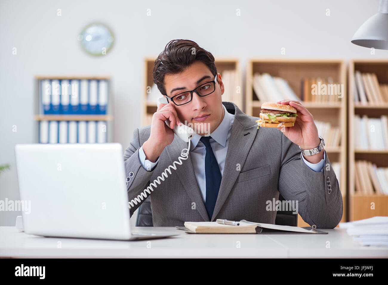 Hungry funny businessman eating junk food sandwich Stock Photo - Alamy
