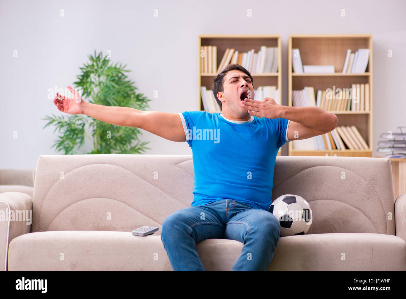 Man watching football at home sitting in couch Stock Photo - Alamy