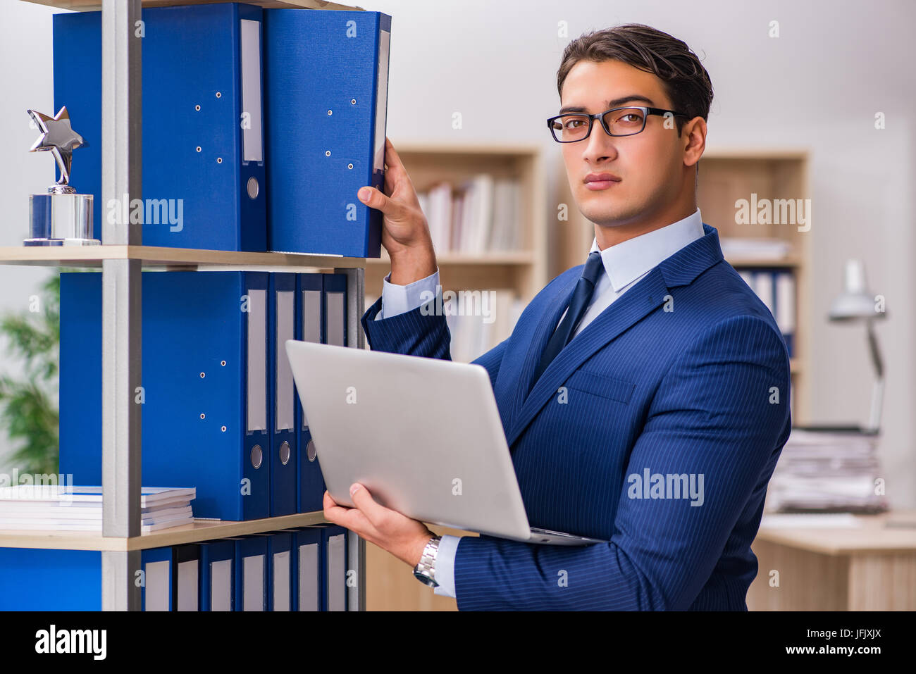 Young man standing next to the shelf with folders Stock Photo - Alamy