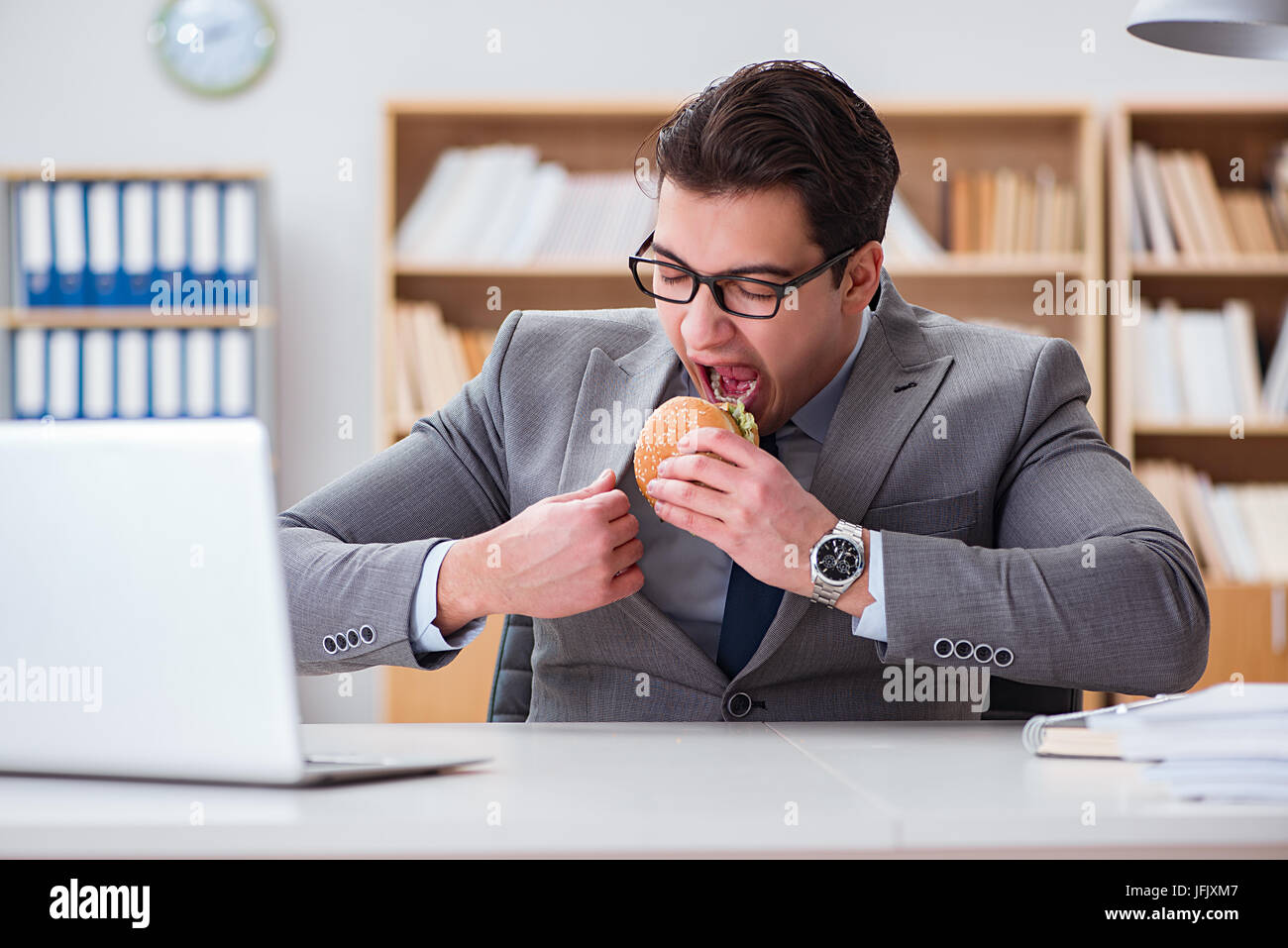 Hungry funny businessman eating junk food sandwich Stock Photo - Alamy