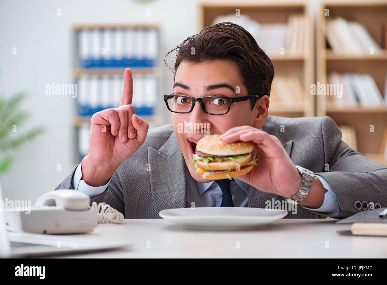 Hungry funny businessman eating junk food sandwich Stock Photo - Alamy