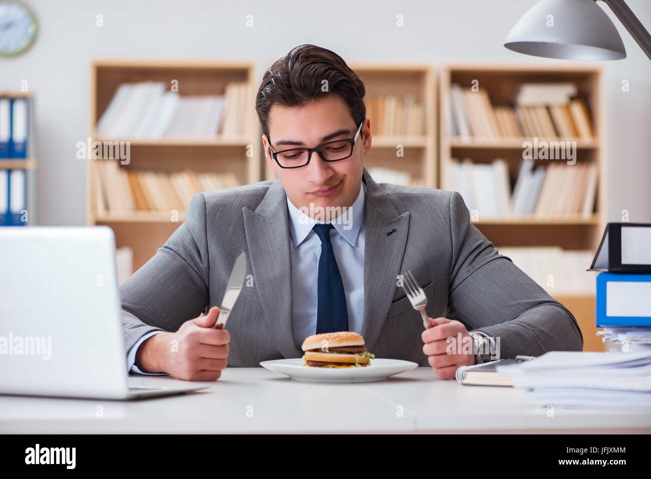 Hungry funny businessman eating junk food sandwich Stock Photo - Alamy