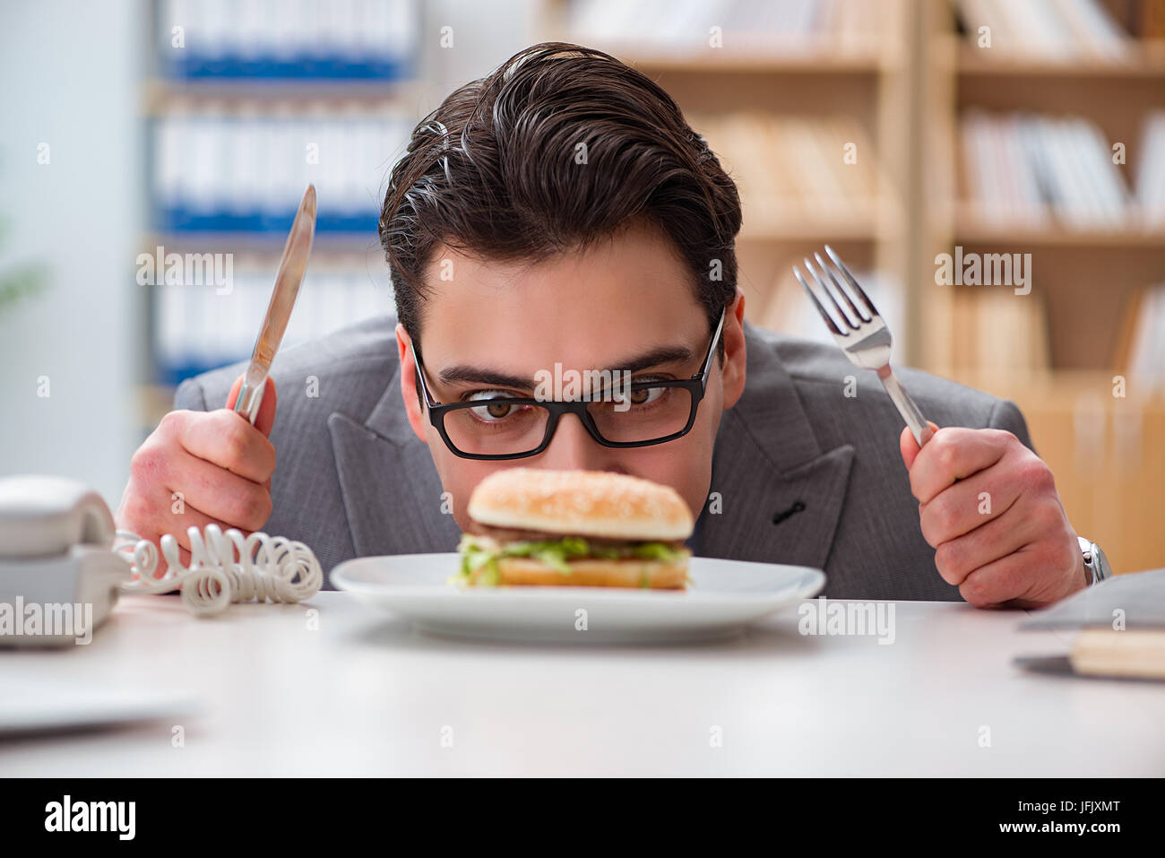 Hungry funny businessman eating junk food sandwich Stock Photo - Alamy