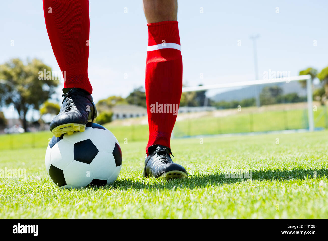 Football player standing with his feet on ball Stock Photo - Alamy