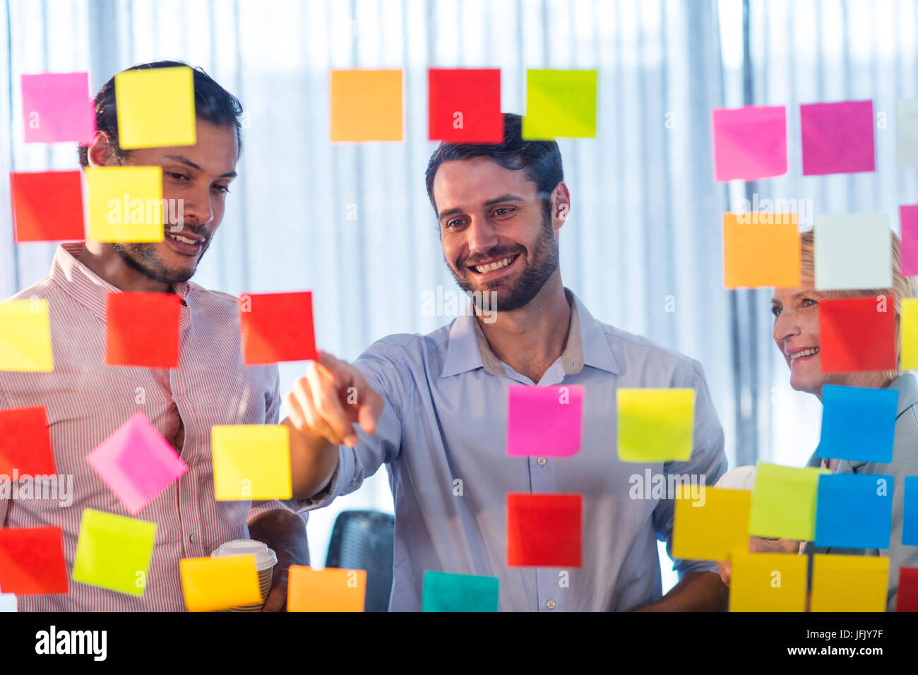 Business people looking at post it on the wall Stock Photo - Alamy