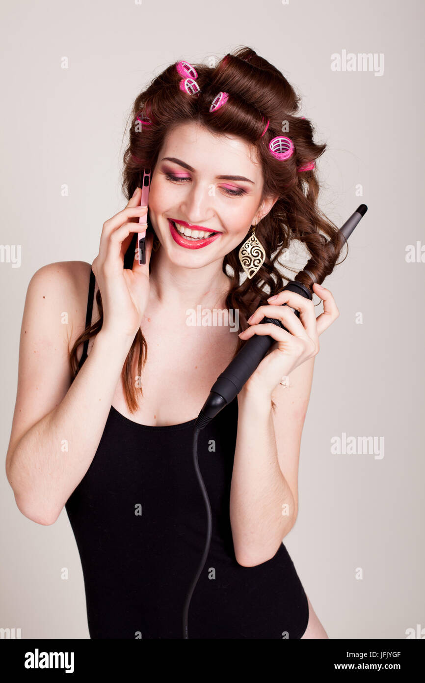 girl with hair curlers talking on the phone and makes the hairstyle ...
