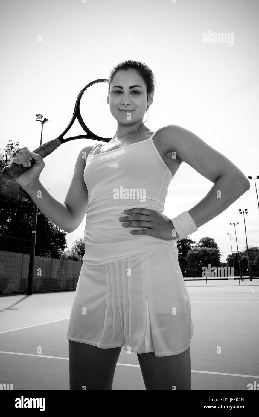 Pretty tennis player holding racket smiling at camera Stock Photo - Alamy