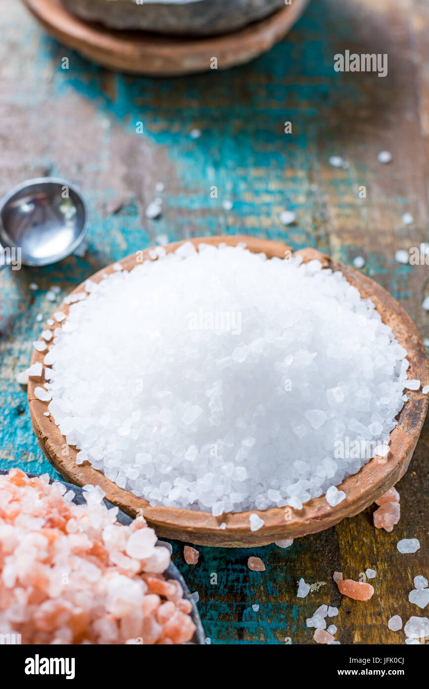 Different types of natural salt in stone bowls on wooden surface. White ...