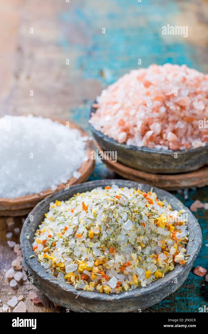 Different types of natural salt in stone bowls on wooden surface. White ...