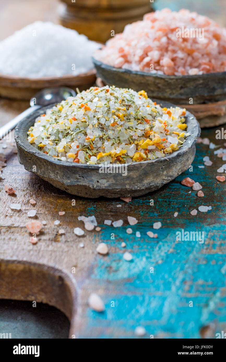 Different types of natural salt in stone bowls on wooden surface. White ...