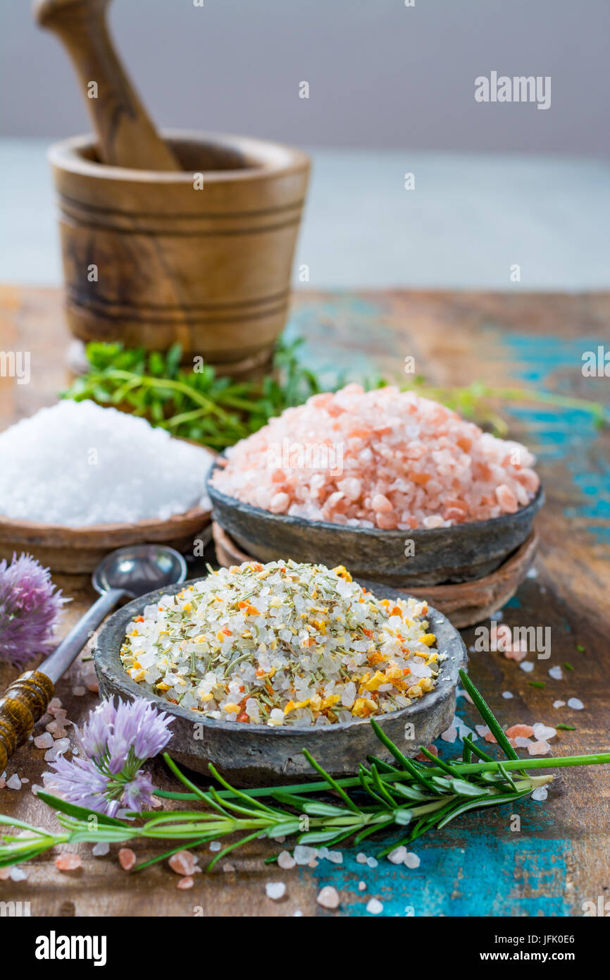 Different types of natural salt in stone bowls on wooden surface. White ...
