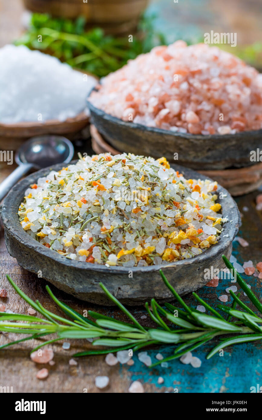 Different types of natural salt in stone bowls on wooden surface. White ...