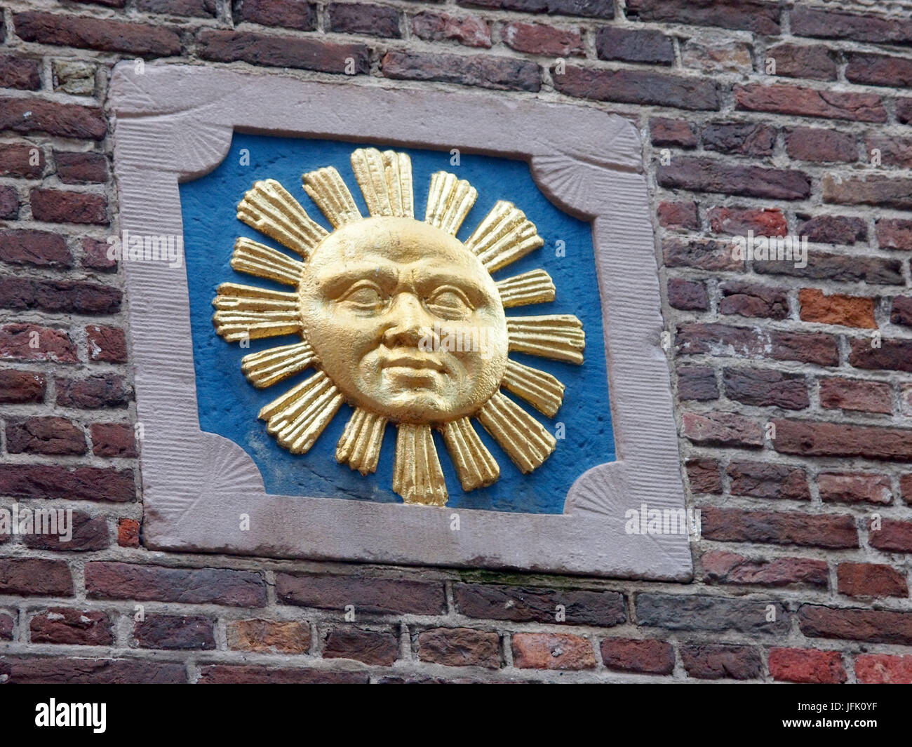 Gold sun face motif set in a blue background on a brick wall Stock ...