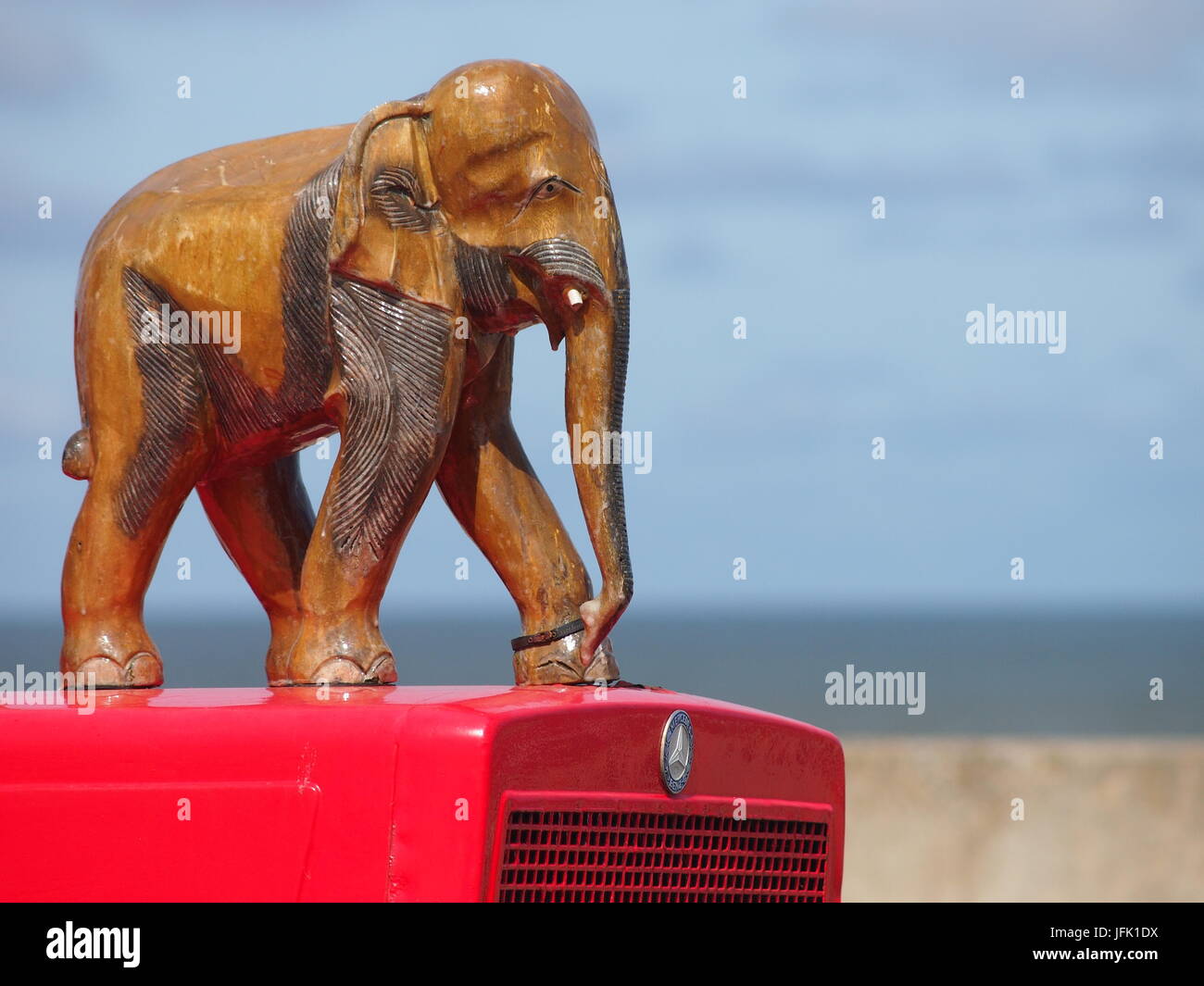 Wooden elephant on the bonet of a red tractor Stock Photo - Alamy