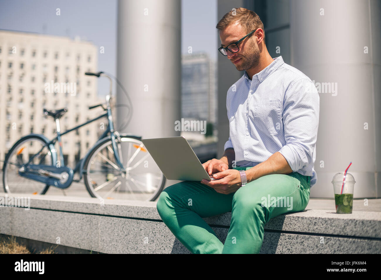 Busy happy man working on laptop outside corporate office Stock Photo ...