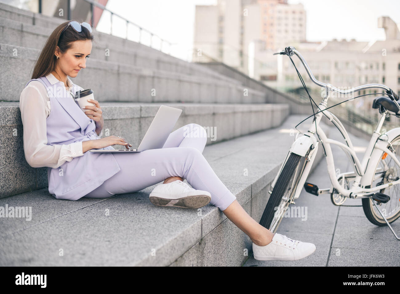 Beautiful woman office worker sitting on the steps and working on a ...