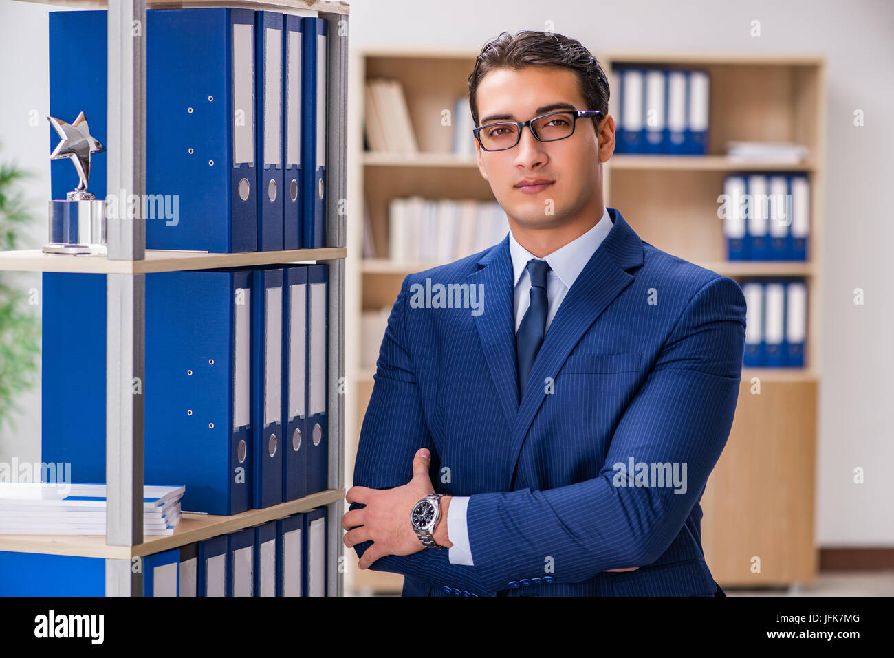 Young man standing next to the shelf with folders Stock Photo - Alamy