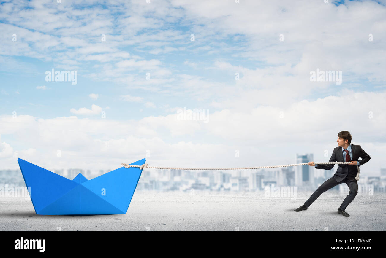 Successful businessman pulling with rope paper boat Stock Photo - Alamy