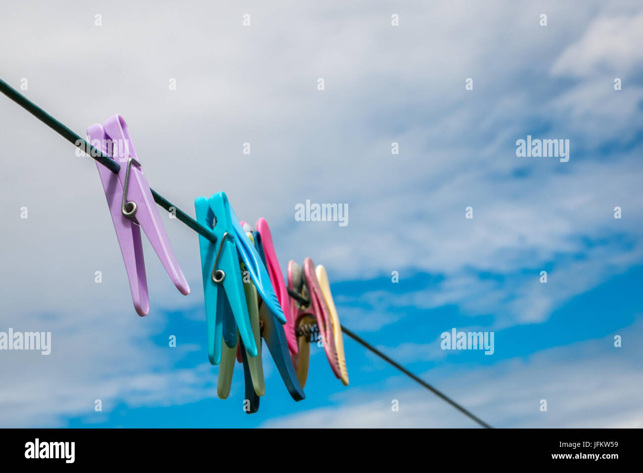 Close up of colourful clothes pegs on a washing line against the sky ...