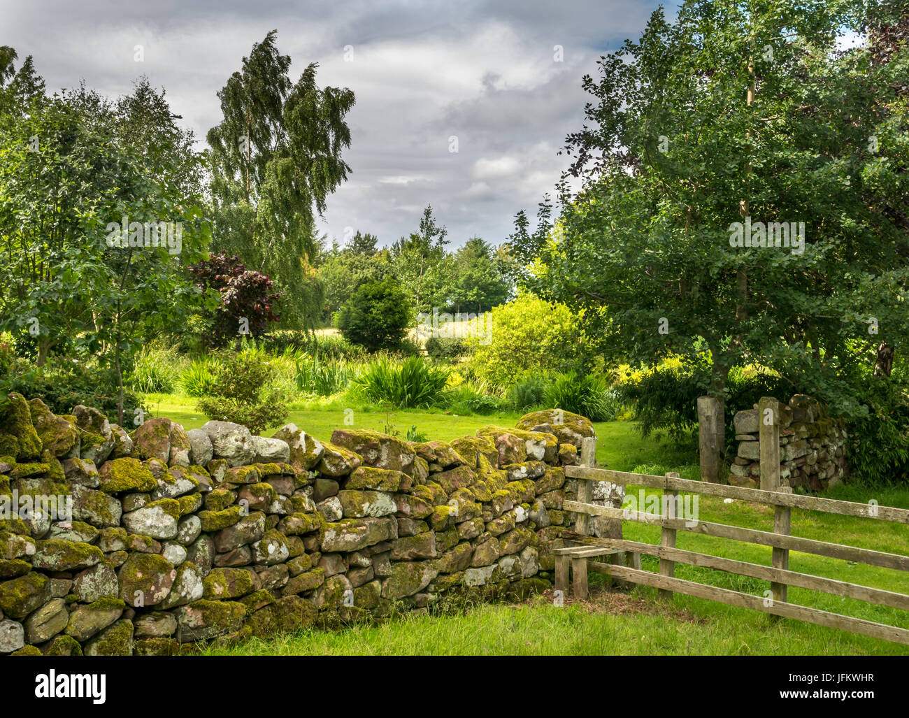 Garden at Garvald Grange with old stone wall, fence and stile, East ...