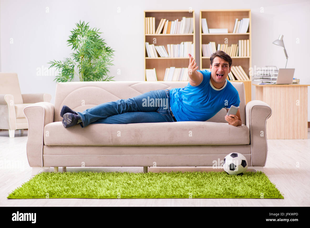 Man watching football at home sitting in couch Stock Photo - Alamy